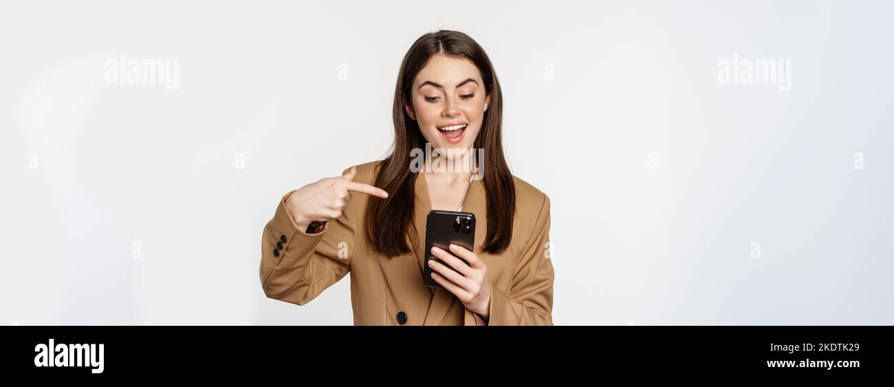 Enthusiastic saleswoman, business woman pointing finger at mobile phone ...
