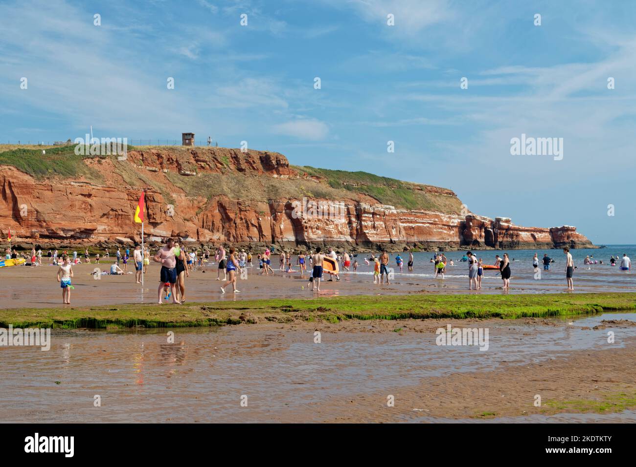 Tourists on Sandy Bay Beach with the red sandstone cliffs of Straight ...