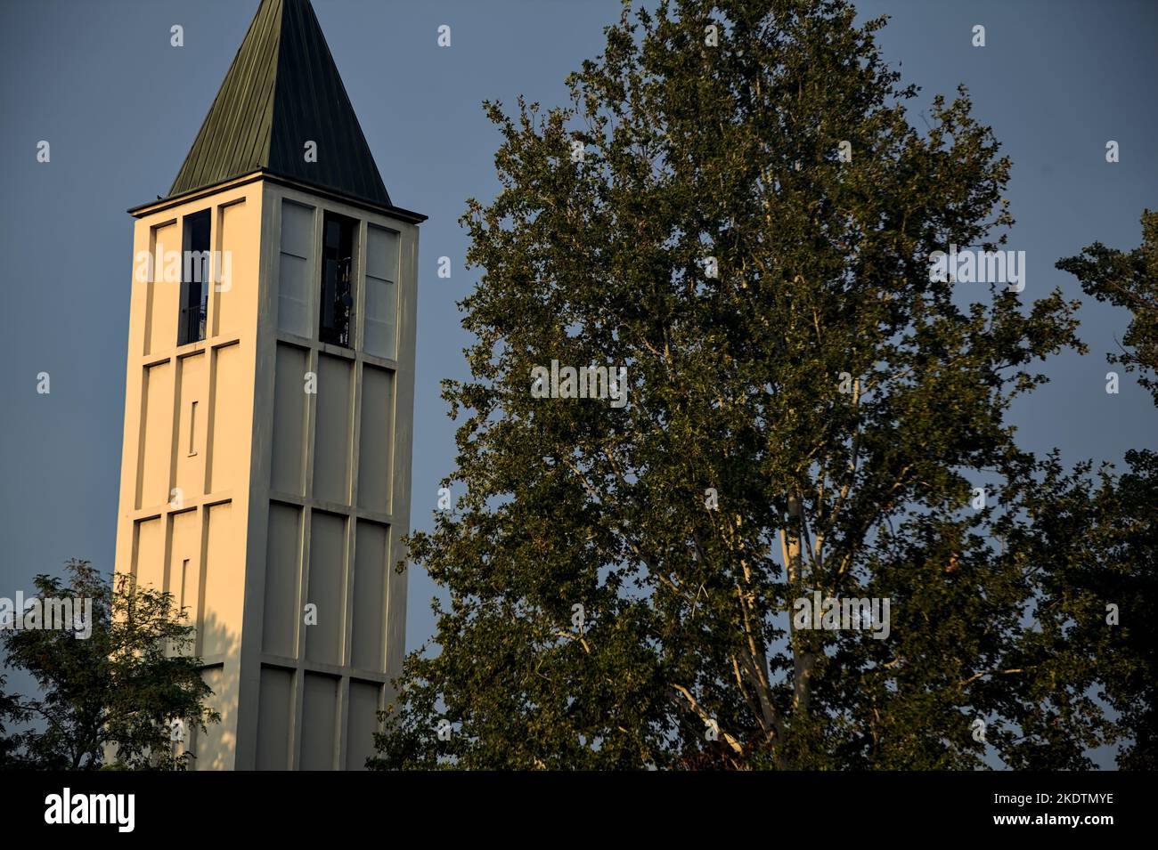 Modern bell tower with a tree at sunset Stock Photo - Alamy
