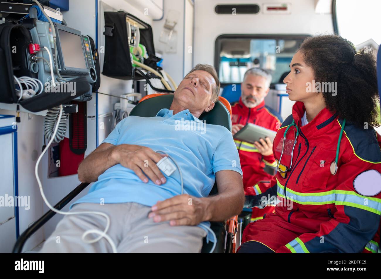 Female paramedic monitoring the patient heart rate using medical ...