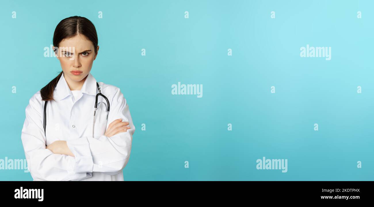 Angry doctor, female medical worker looking offended, cross arms on ...