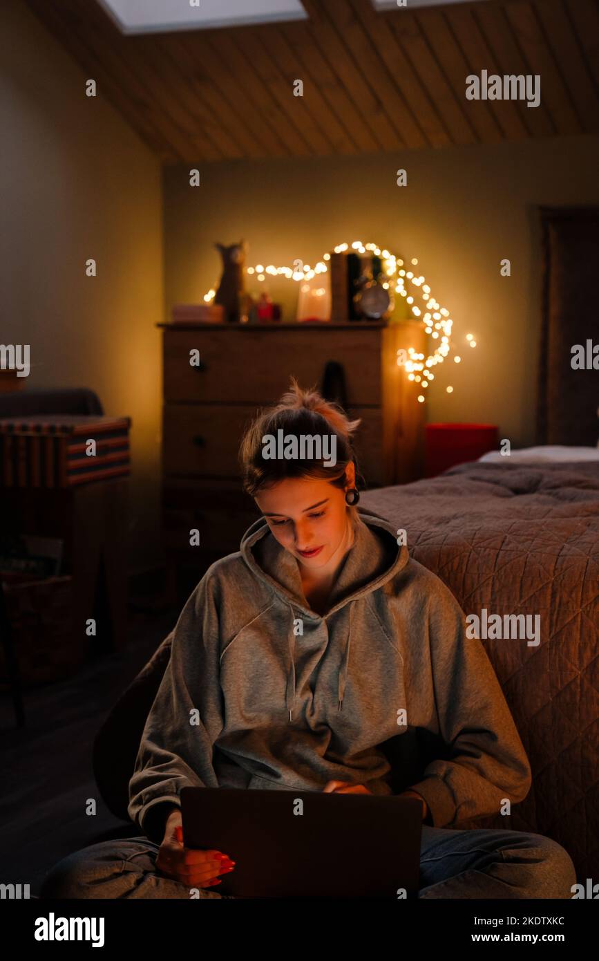 White girl with tunnel rings using laptop while sitting on floor at ...