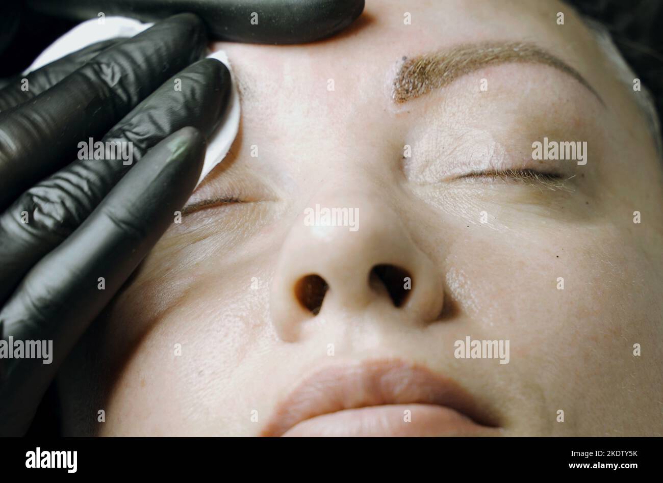 Close-up. The beautician cleans the eyebrows of a woman after the ...