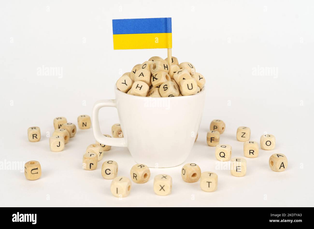 The flag of Ukraine sticks out of a cup with cubes on which letters are ...