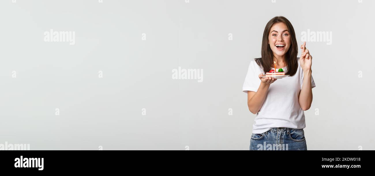 Hopeful and happy smiling birthday girl cross fingers and making wish ...