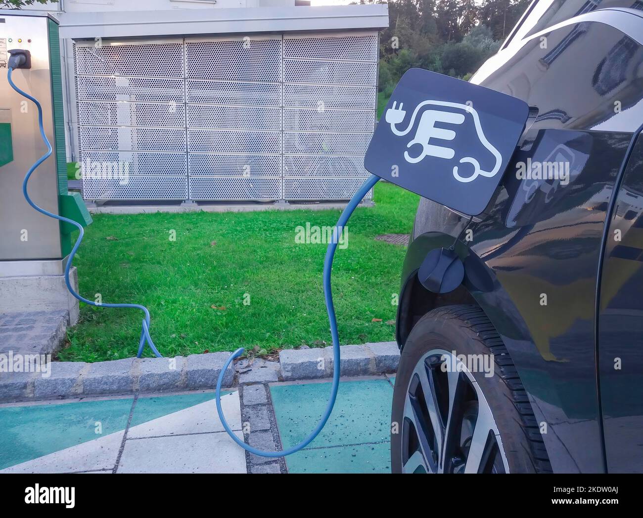 Modern electric car plugged in, charging on the street station. New ...