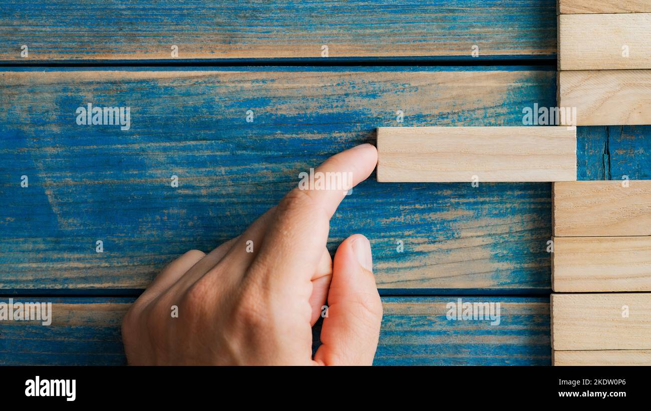 Male finger pushing a black wooden peg into a stack of them in a ...