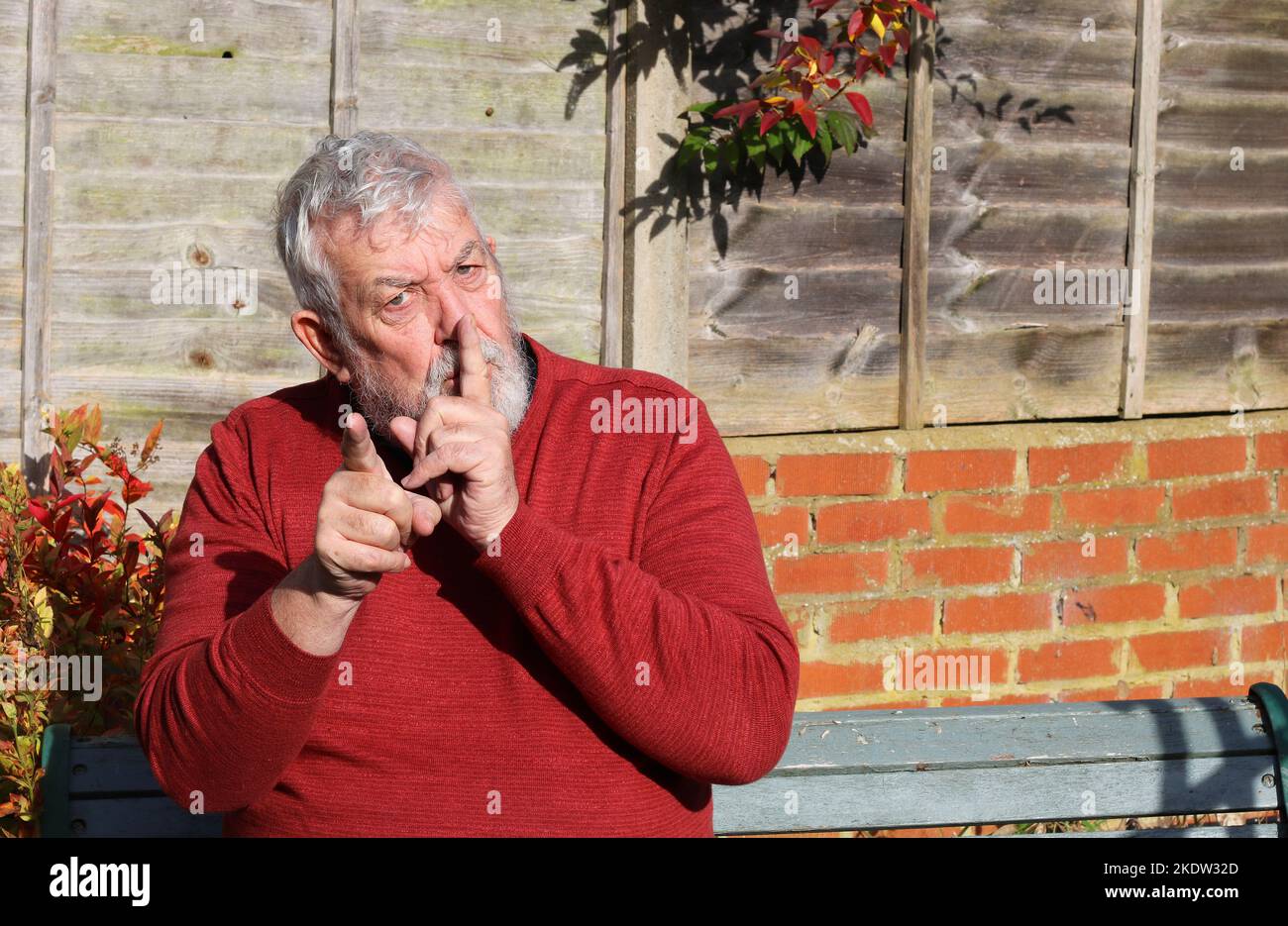 Senior or elderly man with finger to his mouth saying be quiet. Dont ...