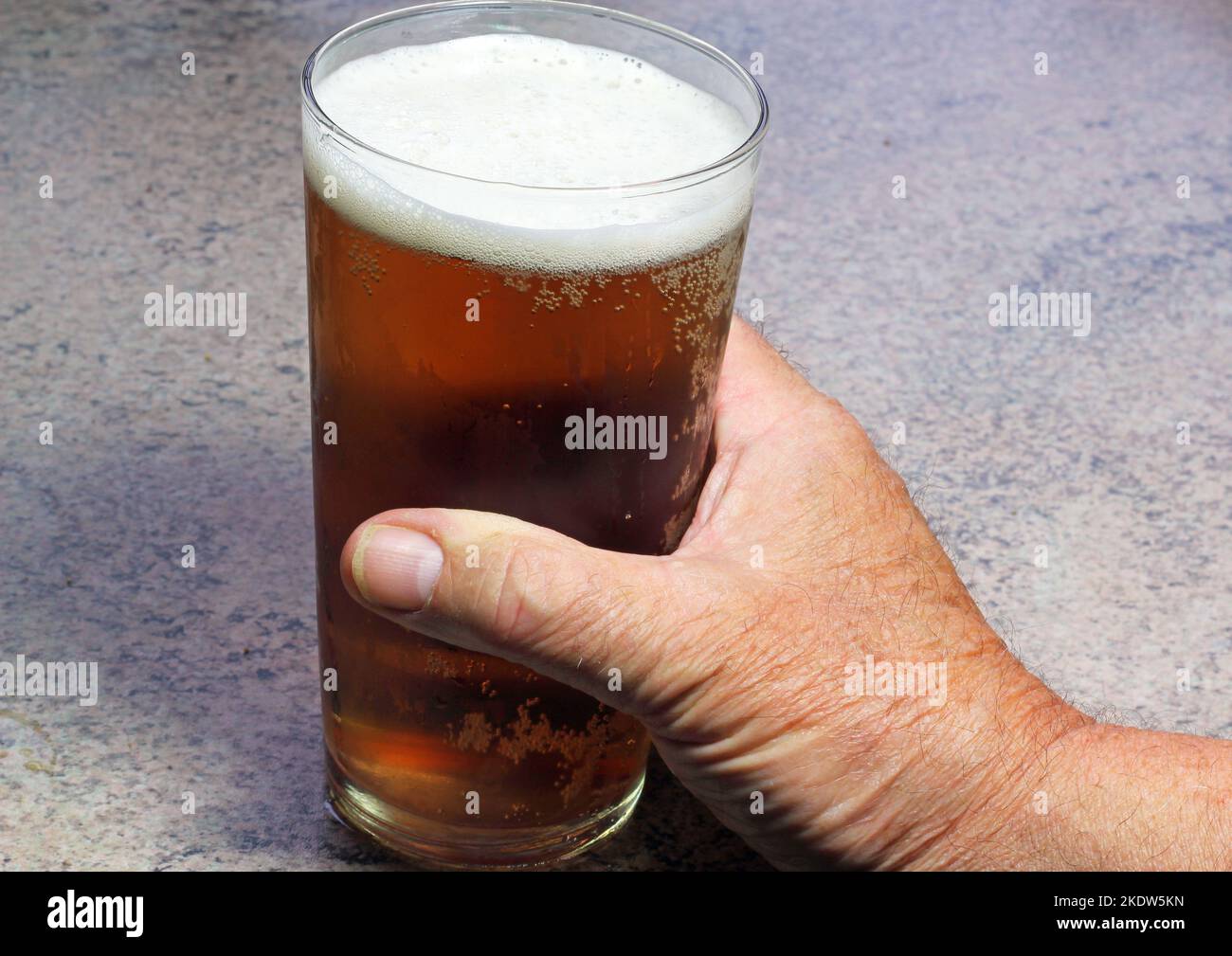 Hand holding a pint glass with amber beer inside the glass Stock Photo ...