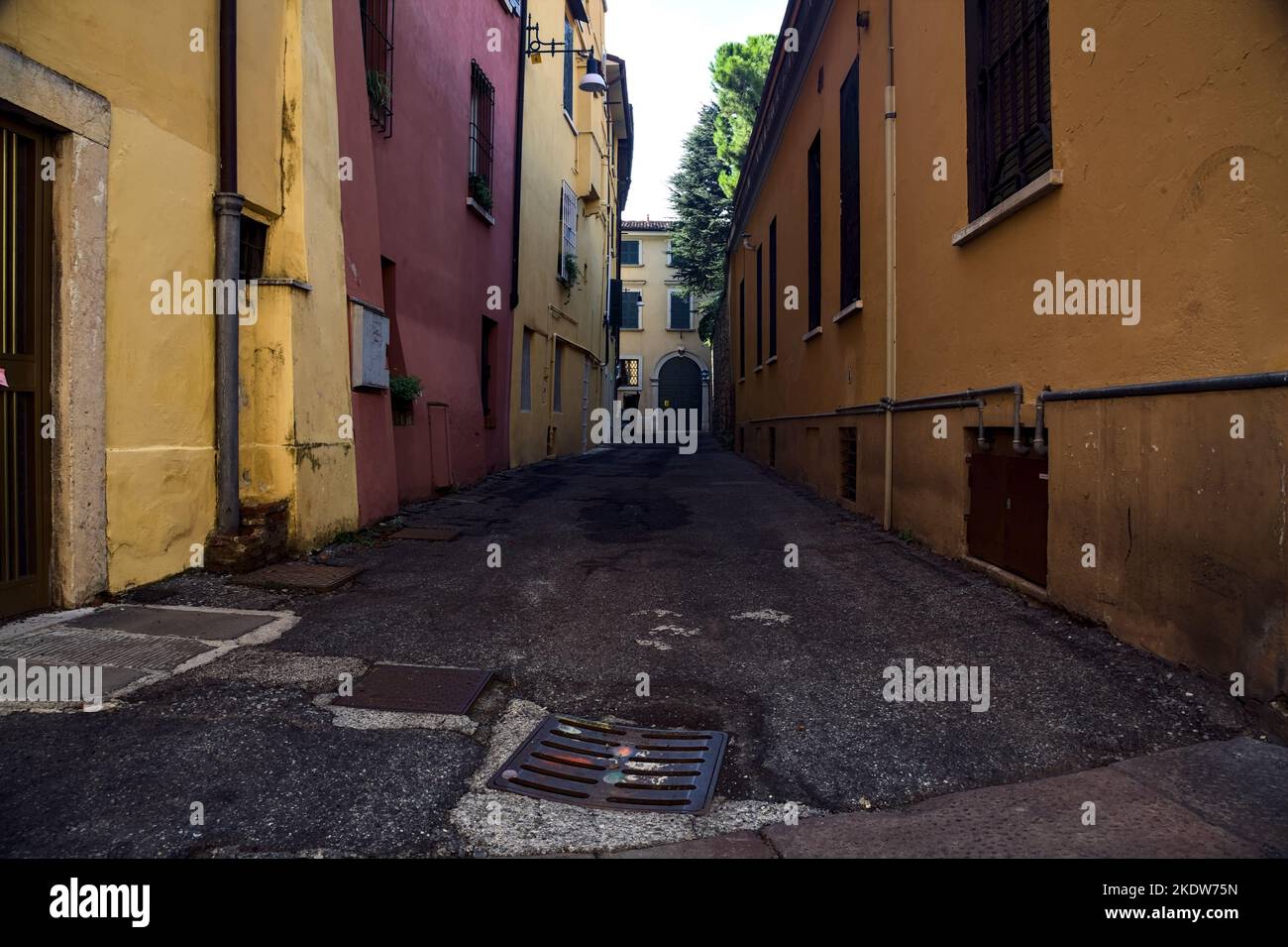 Narrow street in the shade between tall buildings in an italian town ...
