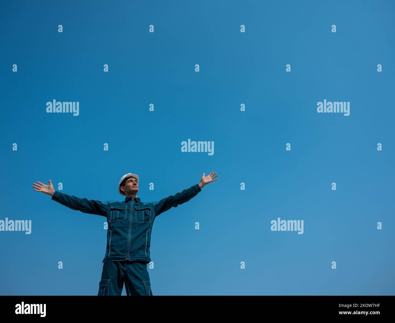 A caucasian man in work clothes and a construction helmet stands ...