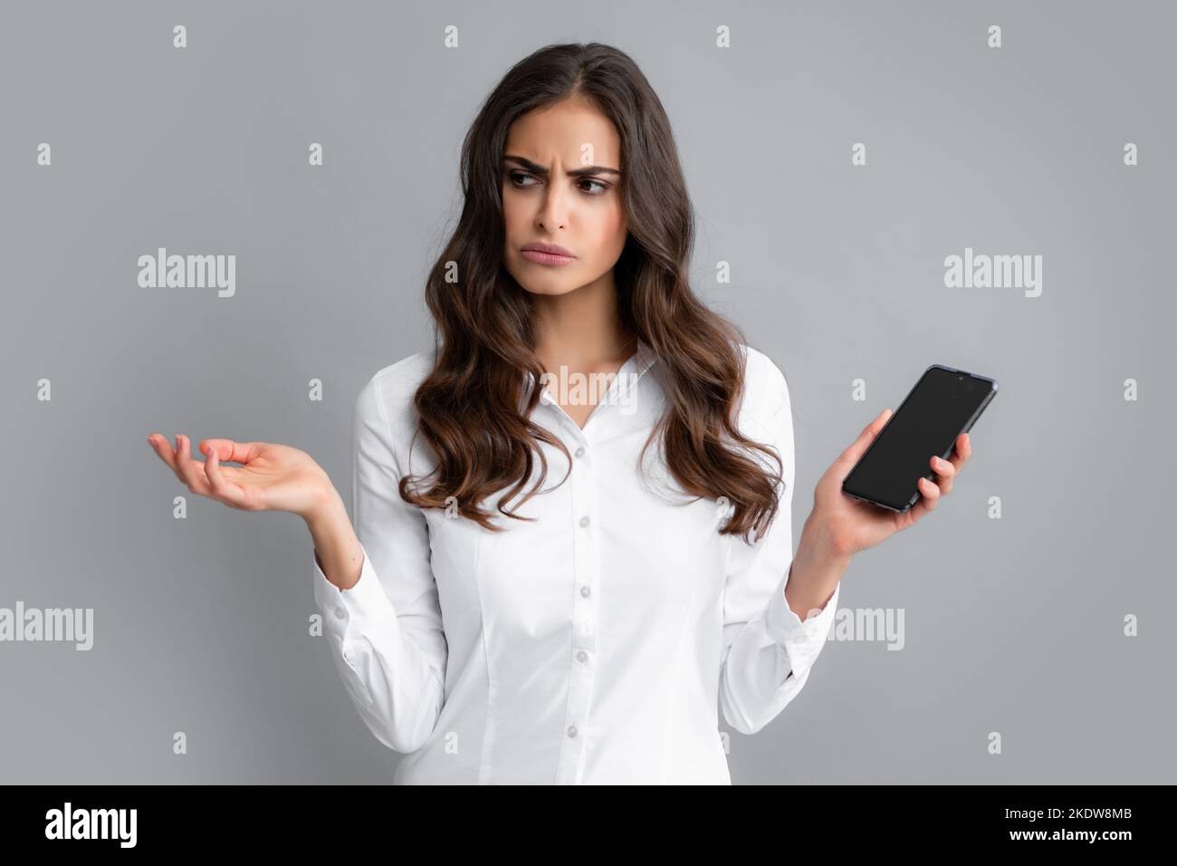 Sad woman with smart phone. Young woman with mobile phone. Serious ...