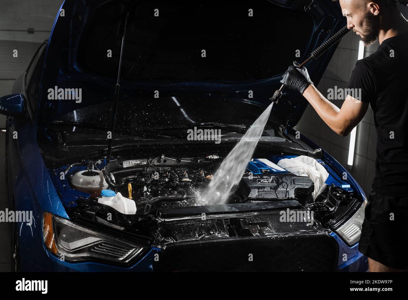Pouring water on car engine. Washing car engine with spray, brush and ...