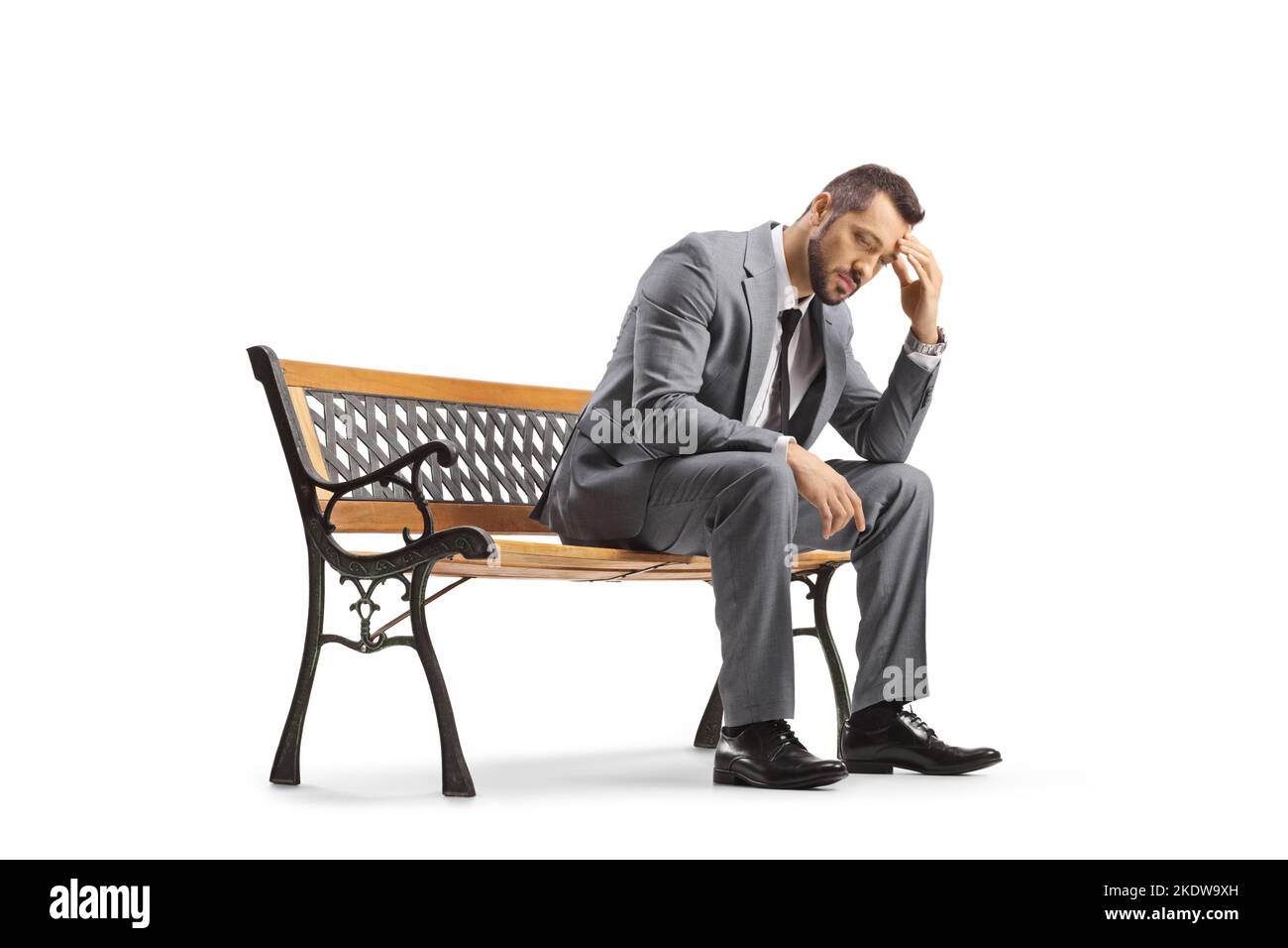 Sad businessman sitting on a bench and holding his head isolated on ...