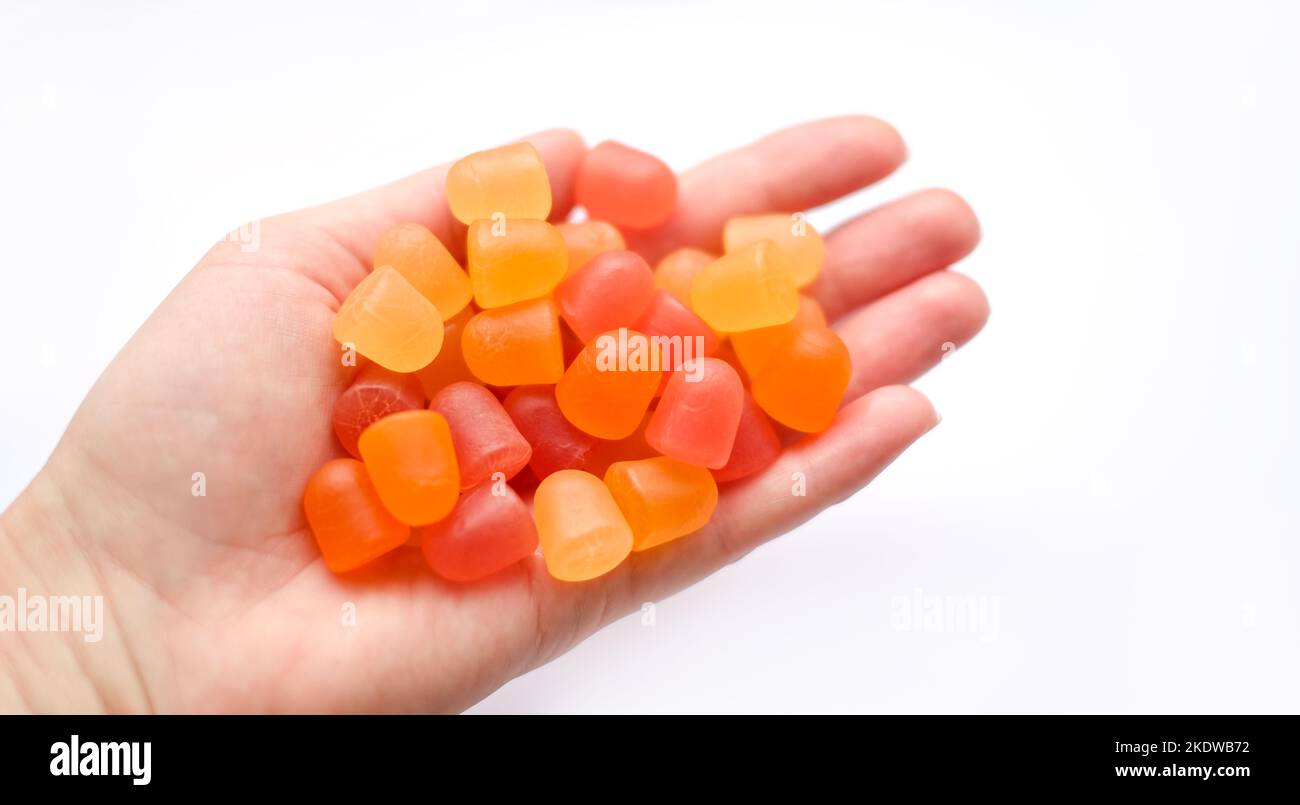 Group of red, orange and yellow multivitamin gummies in the hand ...