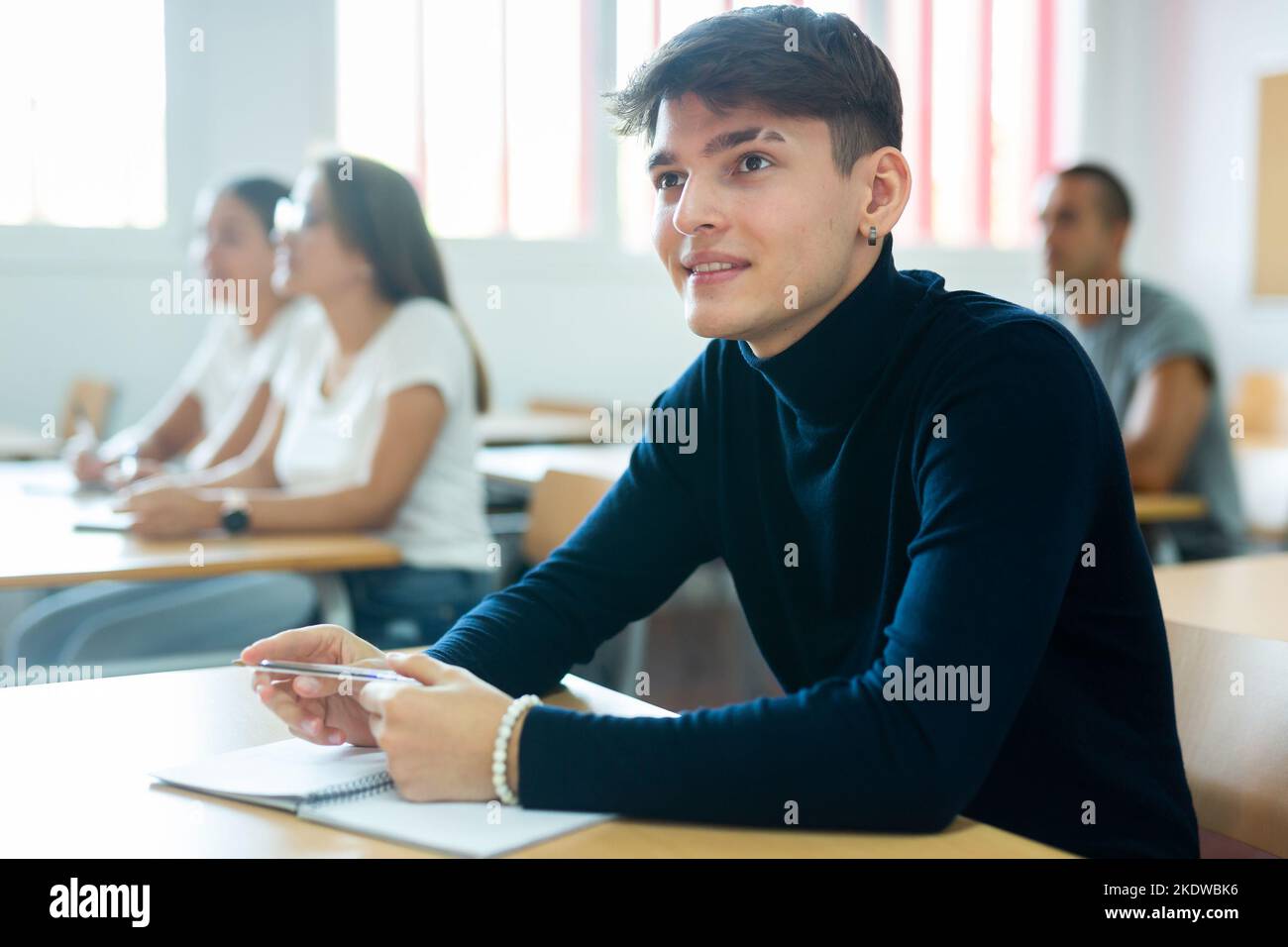 Positive young man attending lecture in college Stock Photo - Alamy