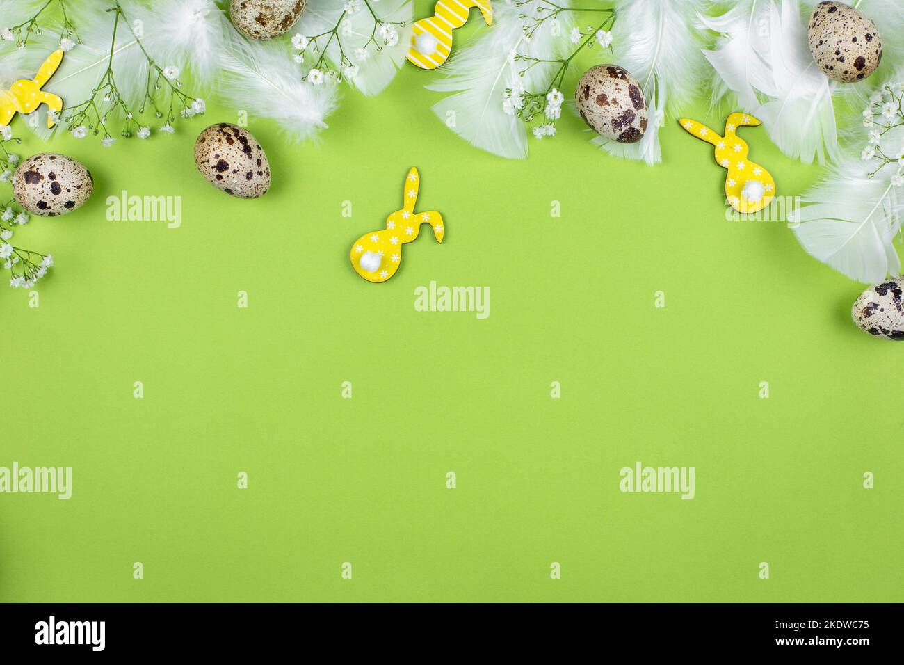 Easter border flat lay with quail eggs, spring flowers, yellow bunnies ...