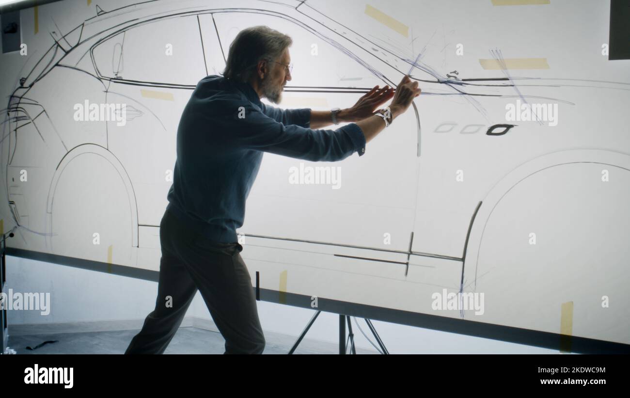 Mature automotive male designer creating sketch with duct tape on paper ...