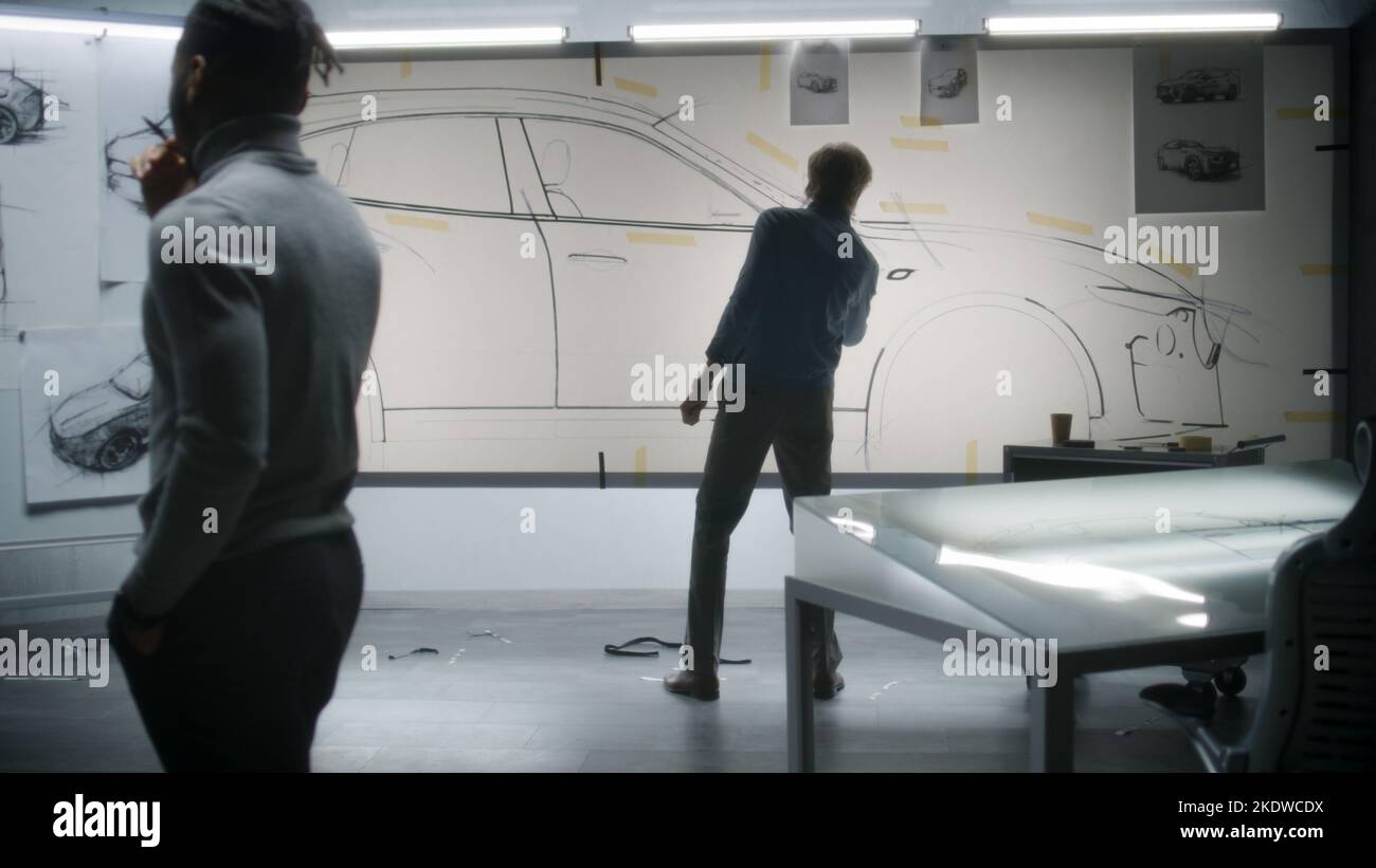 Two diverse automotive male designers drawing sketches with marker on ...
