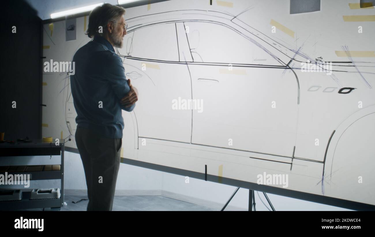 Mature automotive male designer creating sketch with duct tape on paper ...