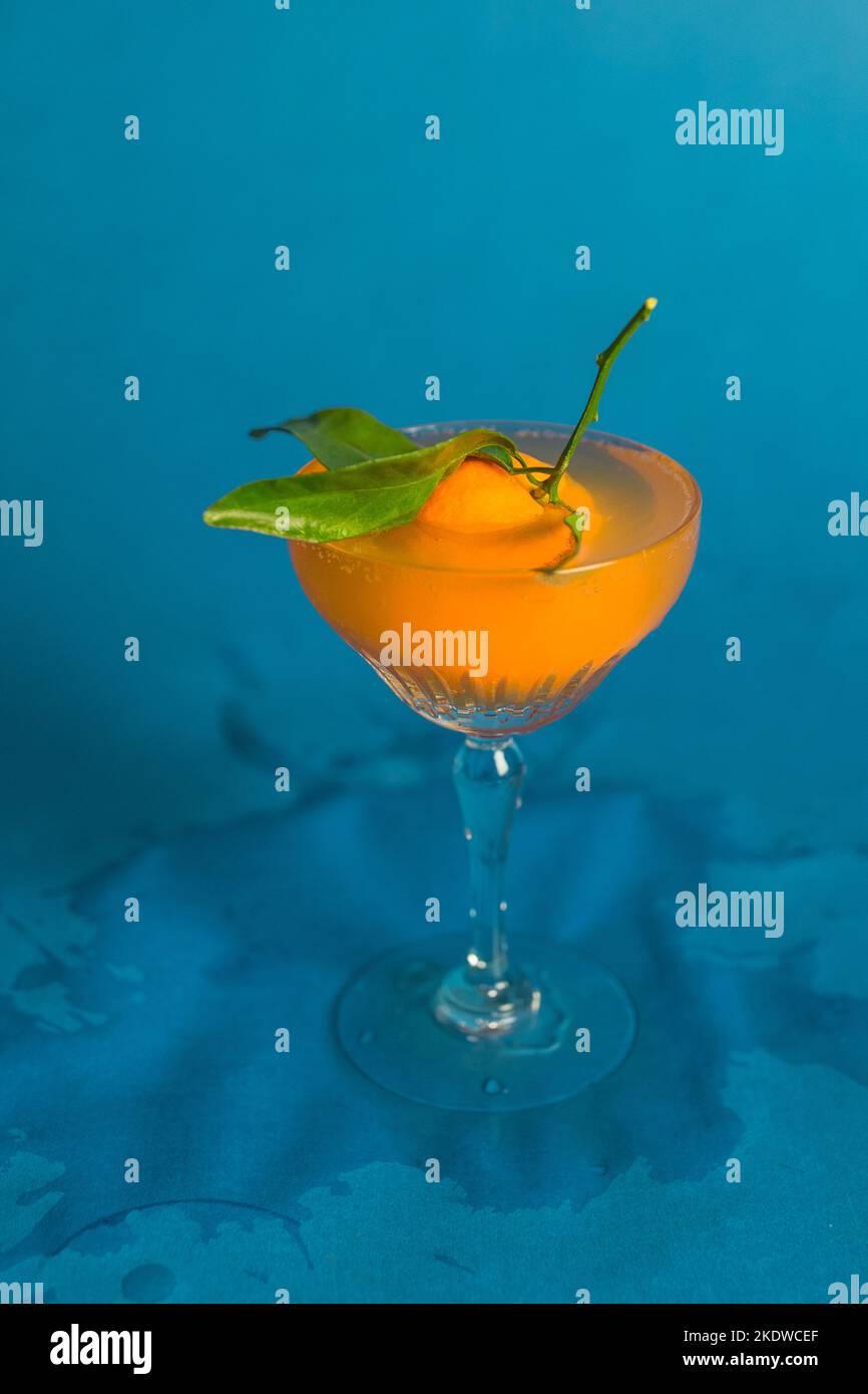 mandarin tangerine dropping into cocktail drink glass splash blue ...