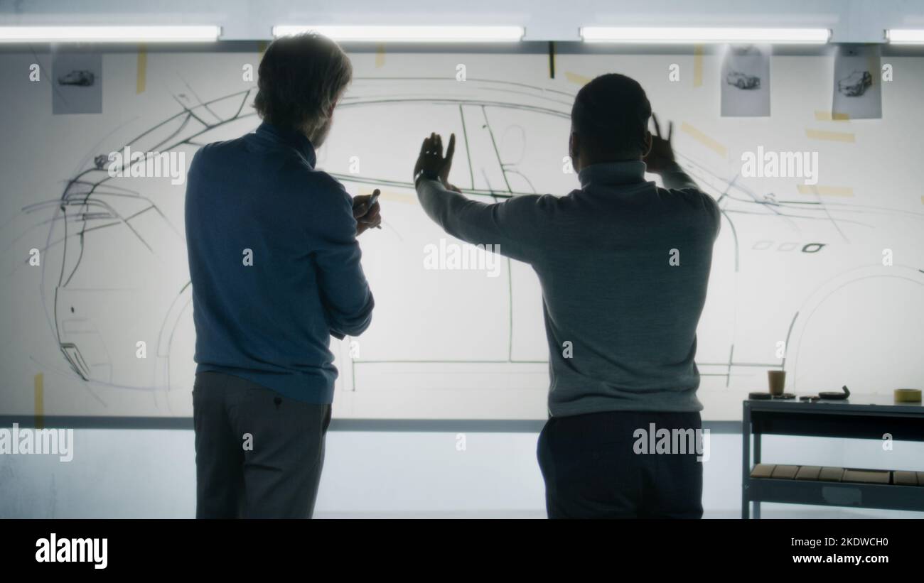 Two diverse automotive male designers standing near sketch on ...