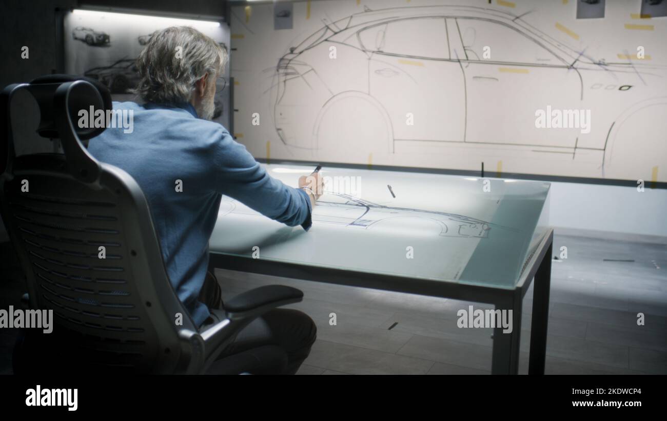 Mature automotive male designer drawing car body sketch with marker at ...