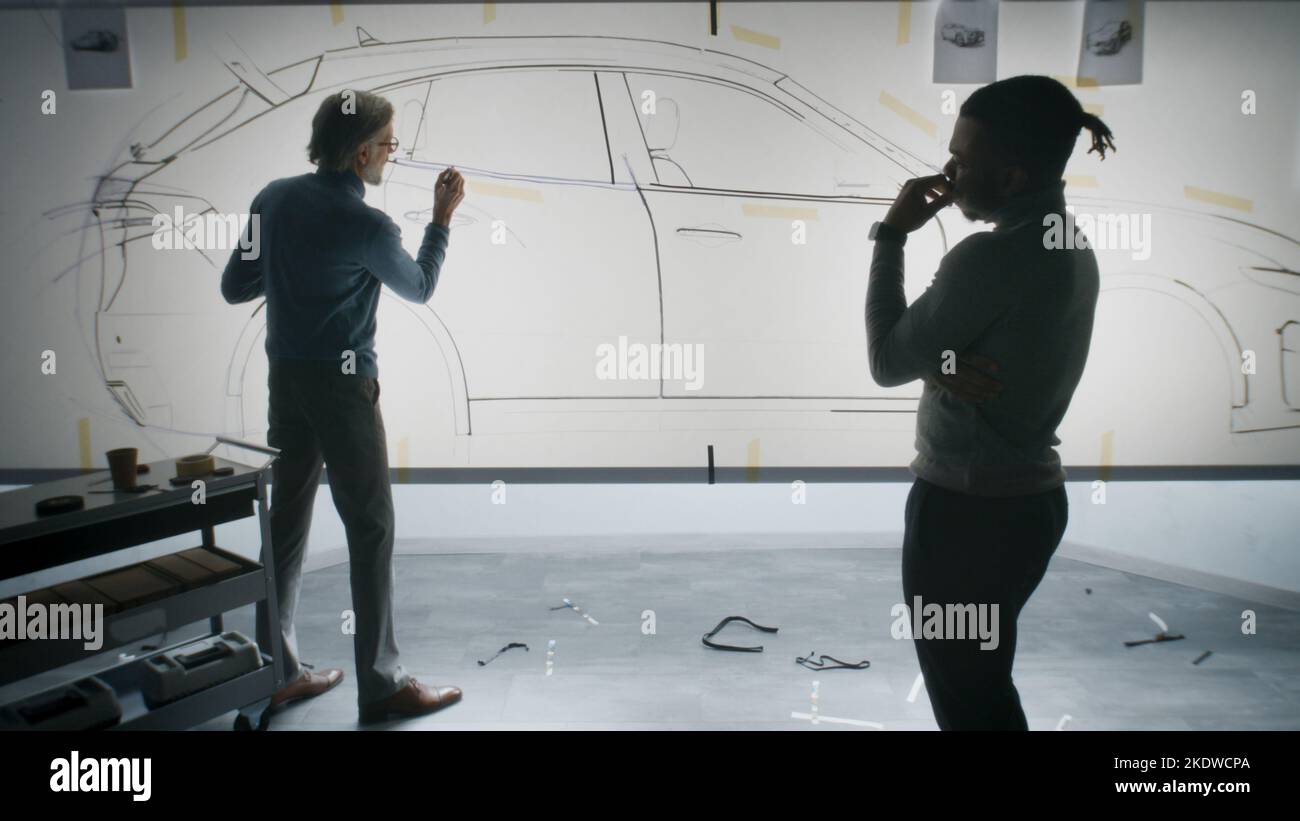Two diverse automotive male designers discussing sketch, drawing with ...