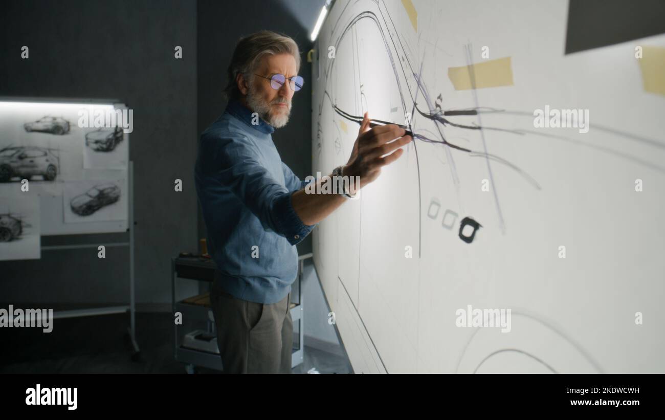 Senior automotive male designer creating sketch with duct tape on paper ...