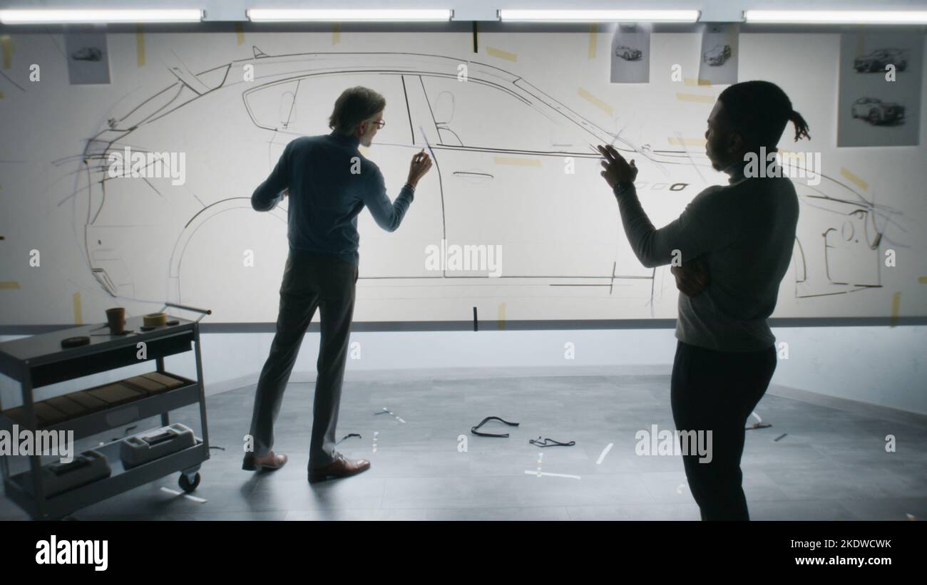 Two diverse automotive male designers discussing sketch, drawing with ...