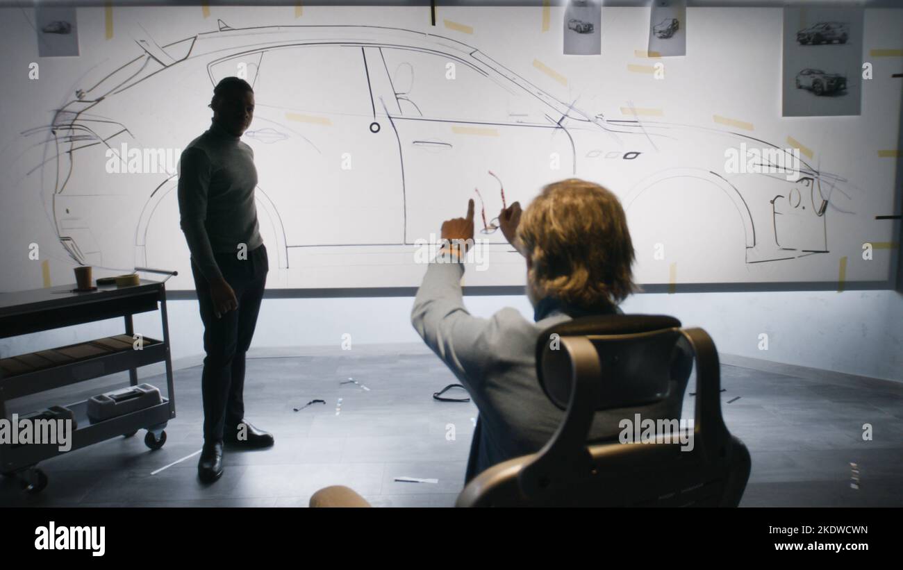 Two diverse automotive male designers discussing sketch blueprint ...
