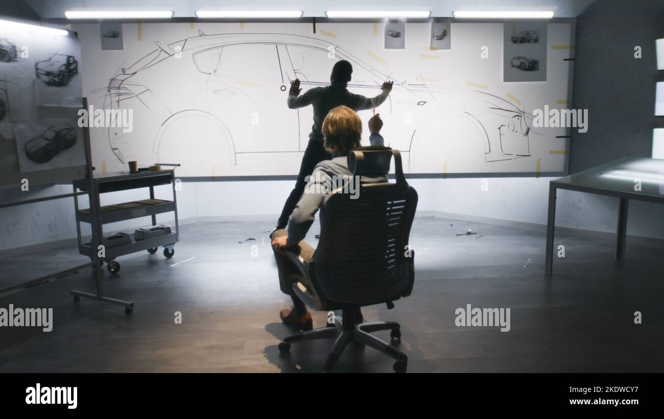 Two diverse automotive male designers discussing sketch blueprint ...