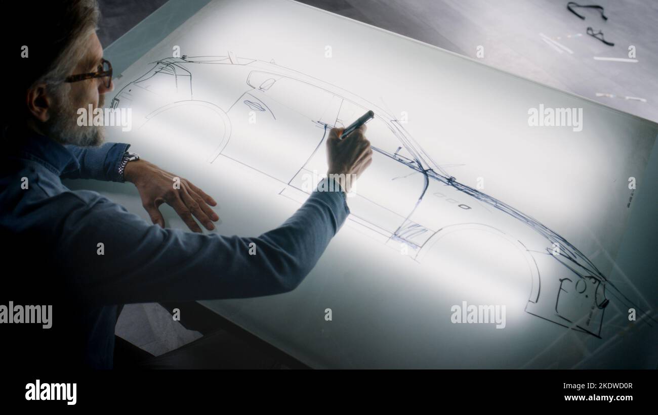 Senior automotive male designer drawing sketch blueprint with marker at ...