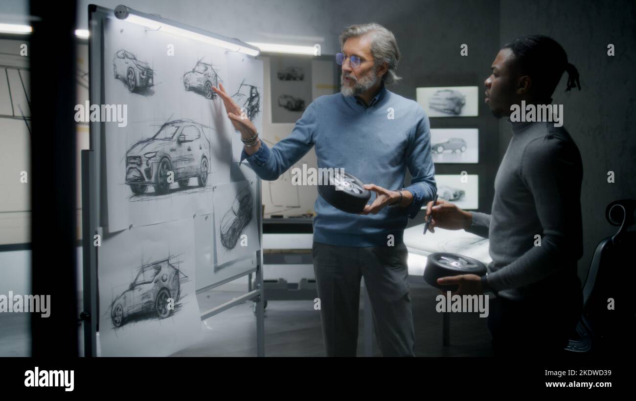 Two diverse automotive male designers holding small wheels, developing ...