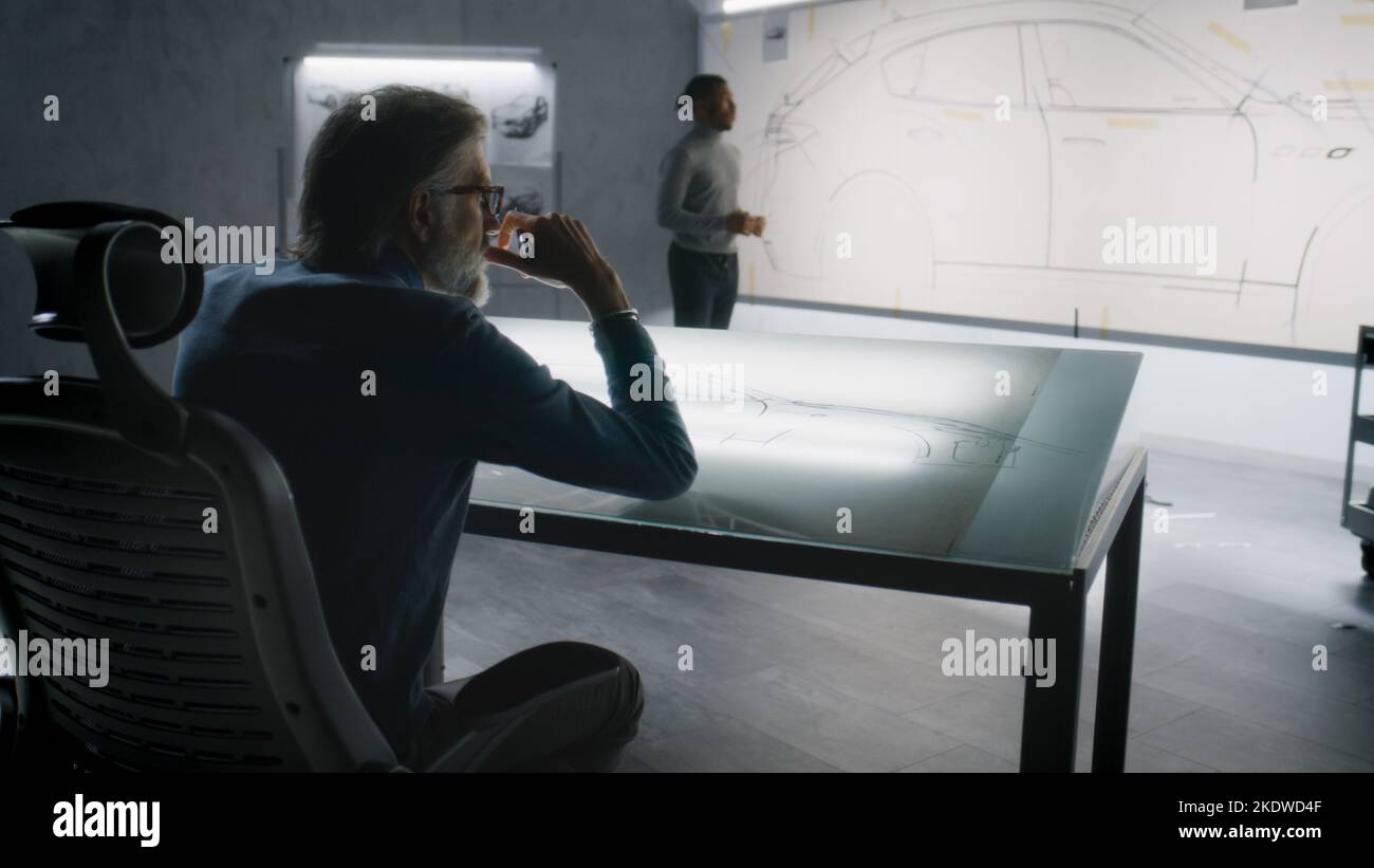 Two diverse automotive male engineers developing sketch of futuristic ...