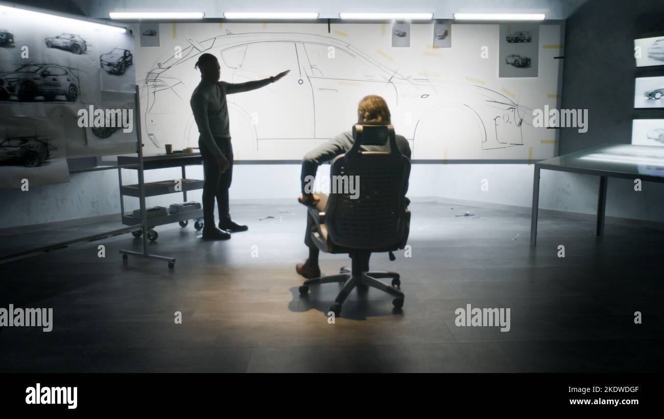 Two diverse automotive male designers discussing sketch blueprint ...