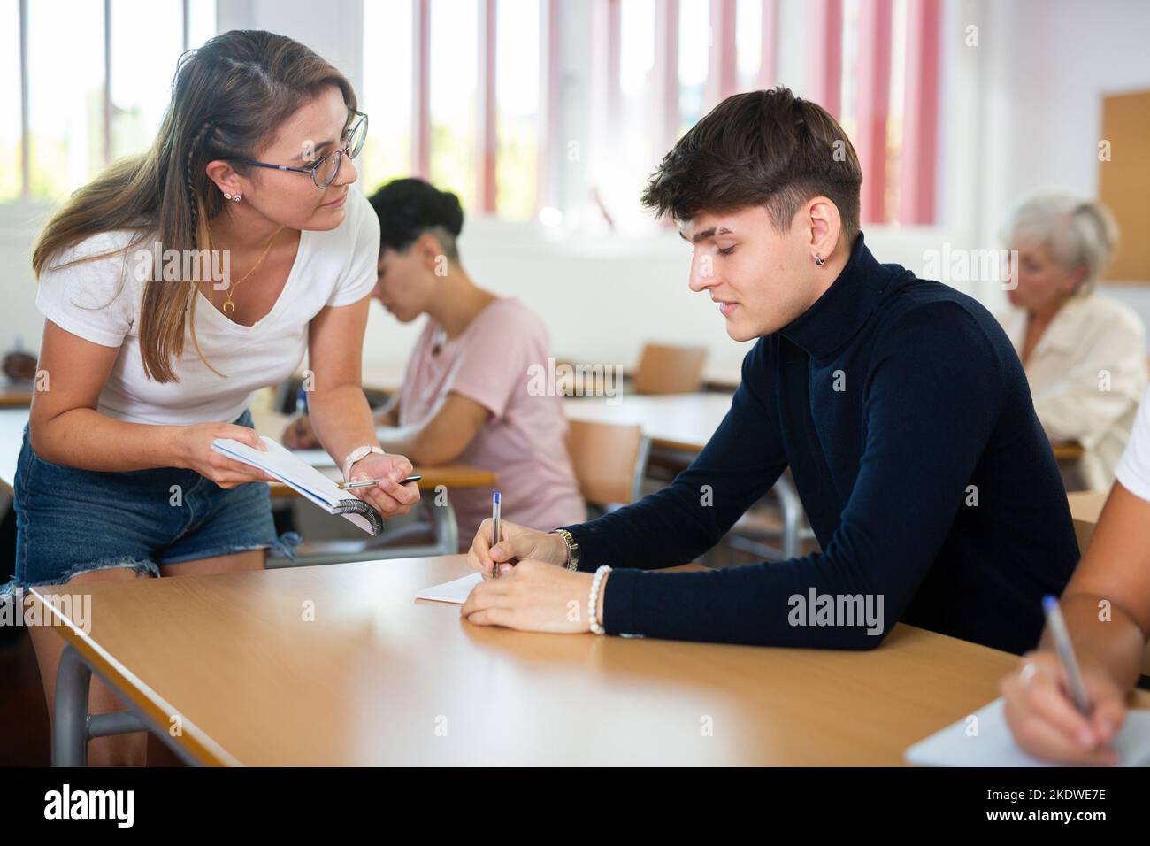 Female student talking to groupmate about study assignment in classroom ...