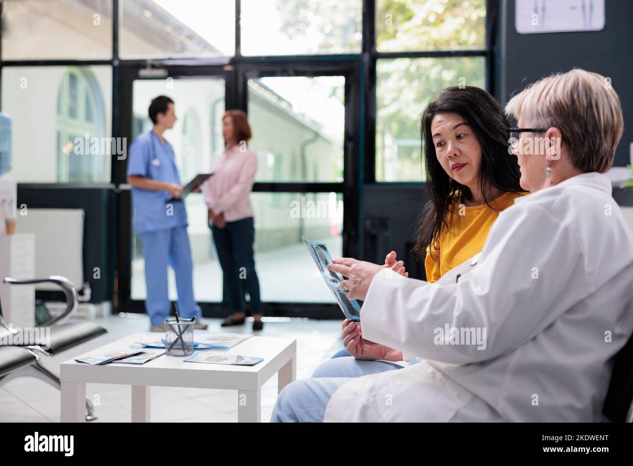 Asian patient looking at medical radiography with senior doctor ...