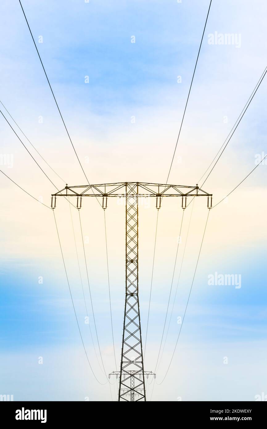High voltage electricity pylon cable line with yellow shine at blue sky ...