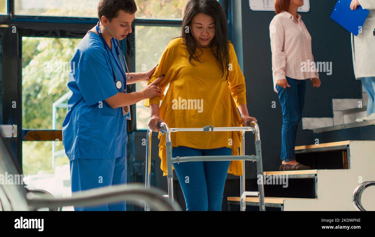 Nurse helping asian woman to walk with walking frame, suffering from ...