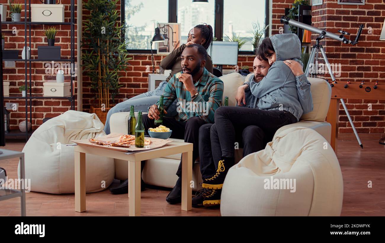 Frightened people watching scary horror movie on television, getting ...