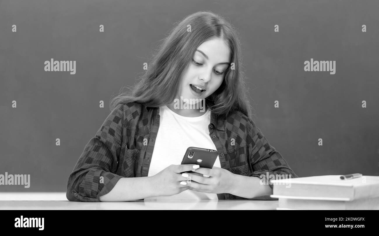 happy kid chatting on smartphone in classroom at blackboard, message ...
