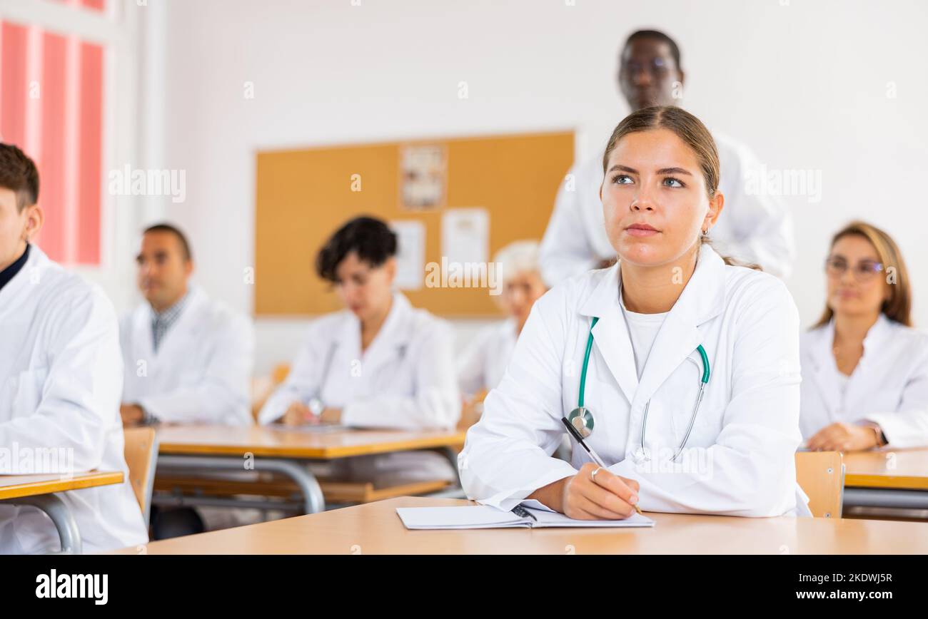 Doctors different age sitting at desk in classroom working during ...