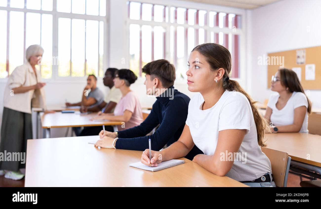Young girl listening to lecture and taking notes in classroom Stock ...
