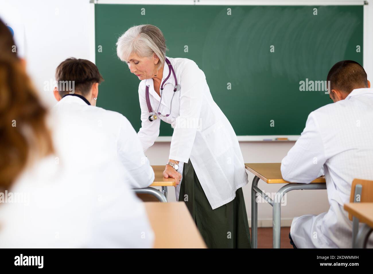 Elderly female professor of medicine giving lecture to students at ...