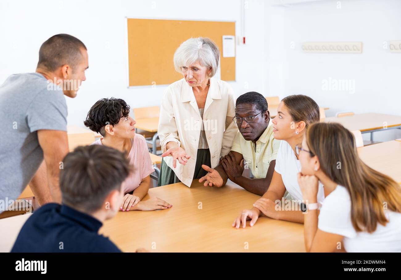Elderly teacher, together with students of different ages, conducts ...