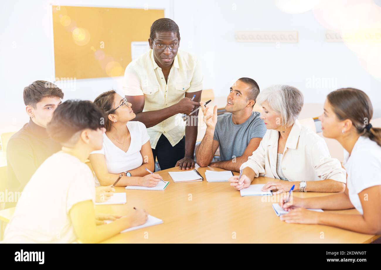 African american male teacher, together with students of different ages ...