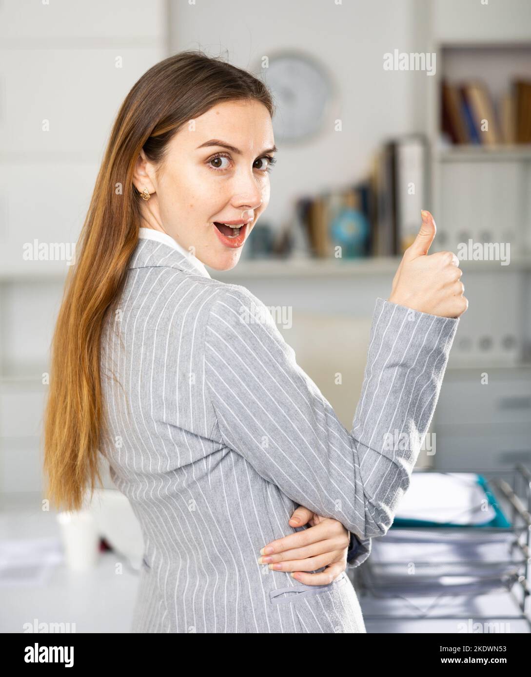 Woman office worker making thumb up gesture Stock Photo - Alamy