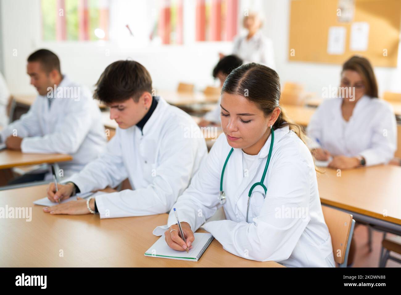 Doctors different age sitting at desk in classroom working during ...