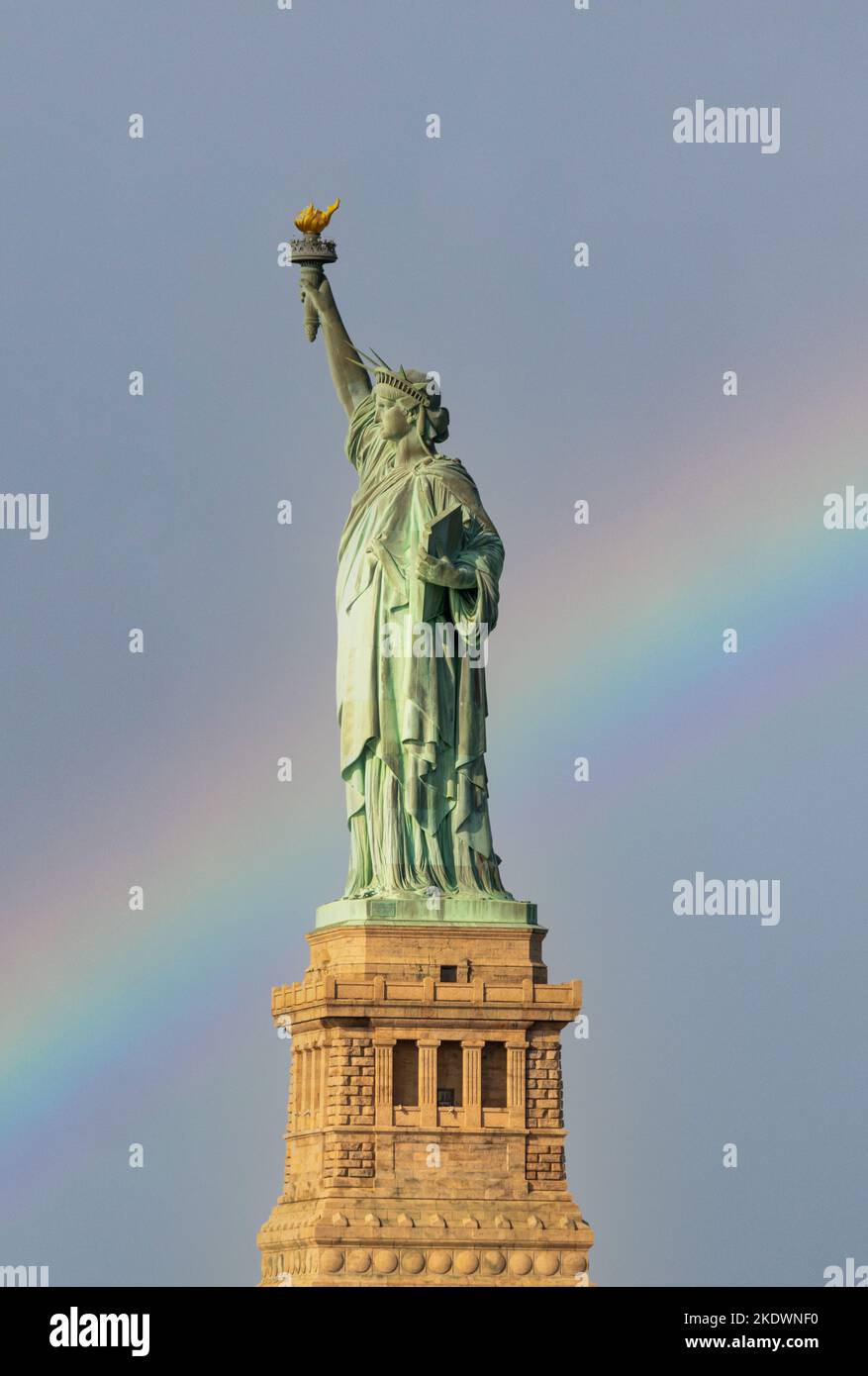 Side view of the Statue of Liberty and a rainbow in the background ...